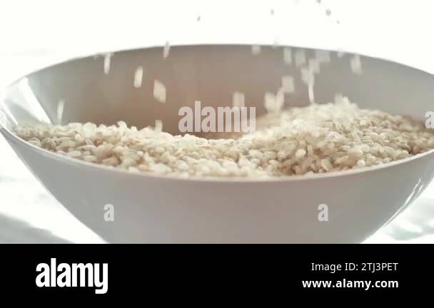 Hands pour rice into a bowl. Slow motion. Round grain white polished ...