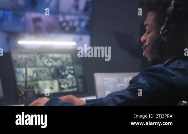 African American officer in headset controls security cameras with AI ...