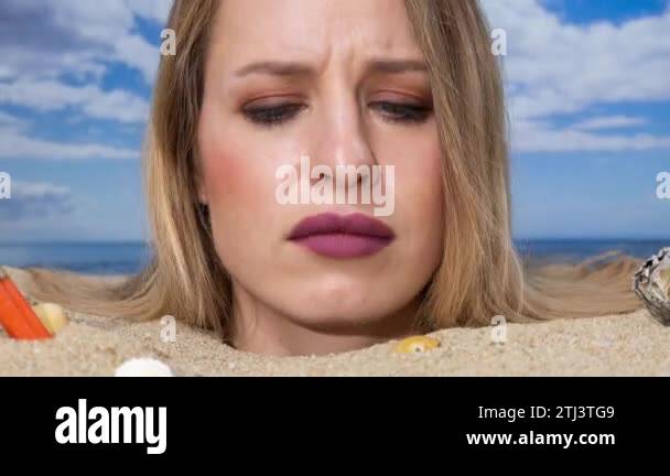 Stop motion of a pretty woman buried up to her head on a beach filling ...