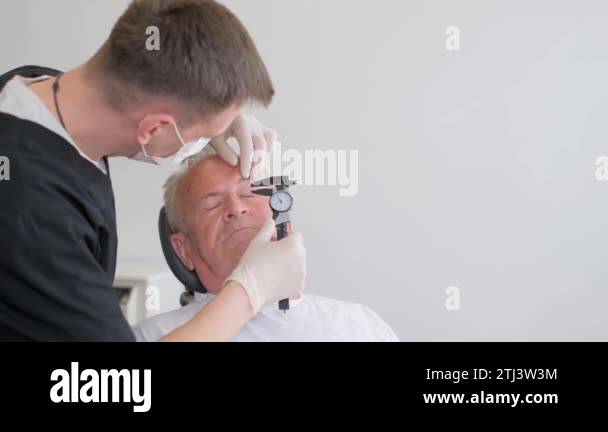 A surgeon is in front of an elderly man and makes marks on his face ...