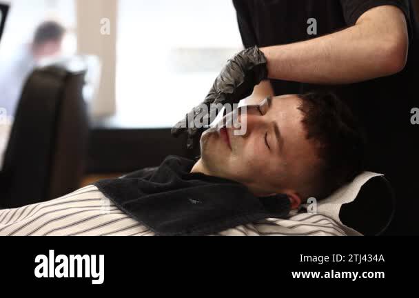 Professional barber shaves customer beard with straight razor. Beard ...