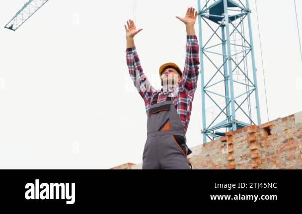 Serious manager in helmet and uniform giving commands to crane operator ...