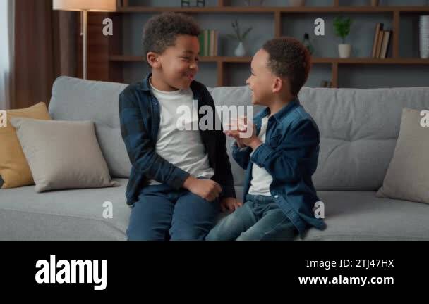 Two little boys brothers children kids siblings at home couch talking ...