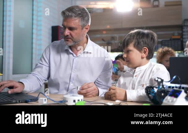 STEM education. Male teacher showing how to programme at laptop and to ...