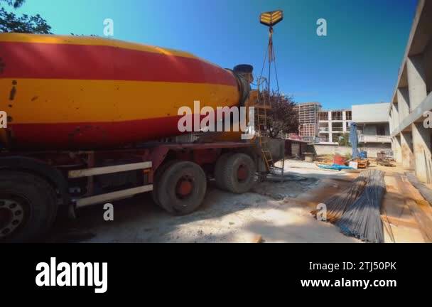 concrete mixer stands on construction site. Crane lifts container ...