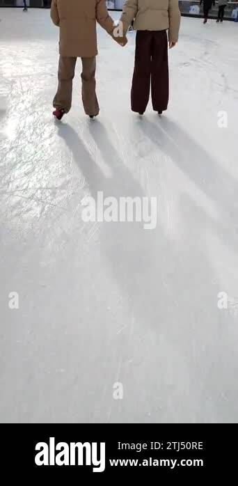 People skating on public open-air ice skating rink in city on winter ...