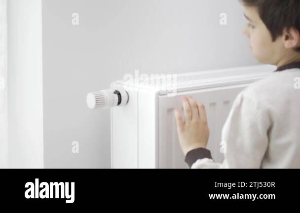 The child touches the cold radiator of the home heater with frozen ...