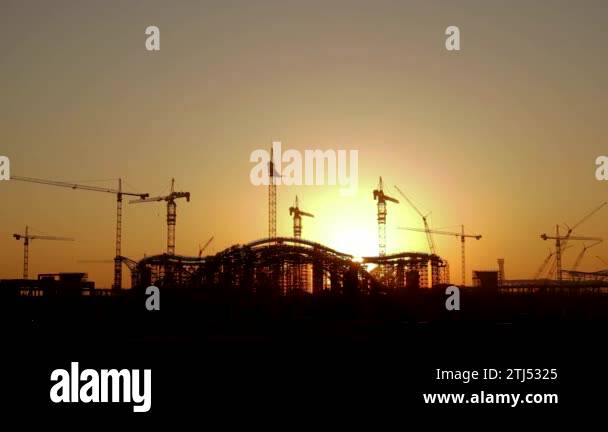 The rising sun appears from behind a silhouette building of the ...