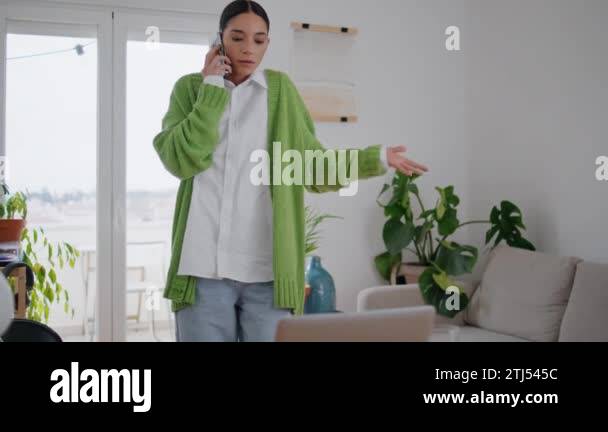 Gesturing businesswoman calling mobile phone walking at room. Confused ...