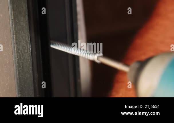Worker tightening screw with screwdriver, installing window frame ...
