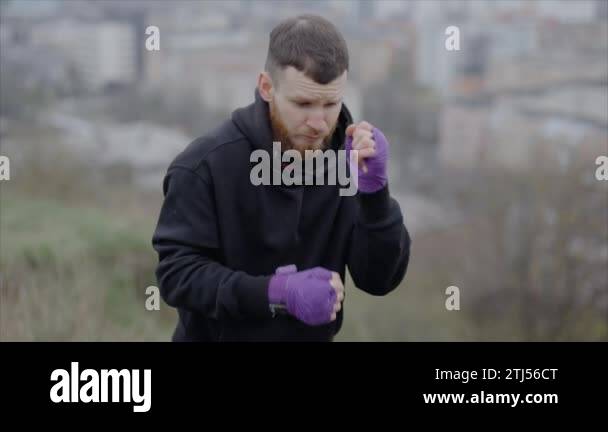 Man boxer is engaged in sports training outdoors in the city, slow ...