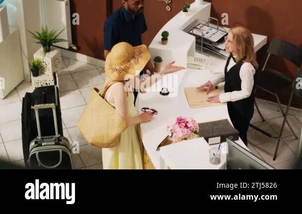 Receptionist welcoming hotel guests upon their arrival, talking to them ...