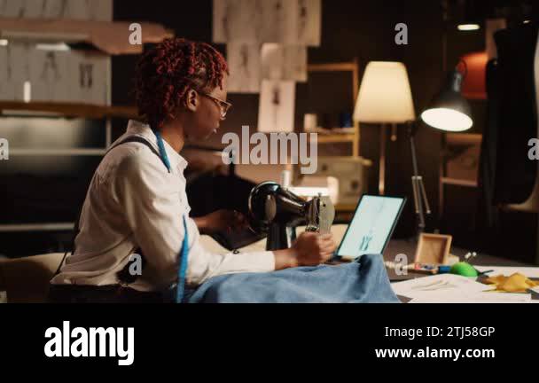 Atelier employee using sewing machine to create new custom made clothes ...