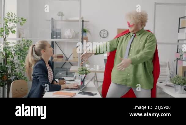 Super hero in costume is running in office helping employees bringing ...