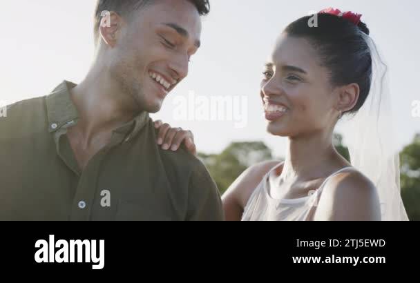 Happy diverse bride and groom laughing and showing wedding rings at beach wedding, in slow ...