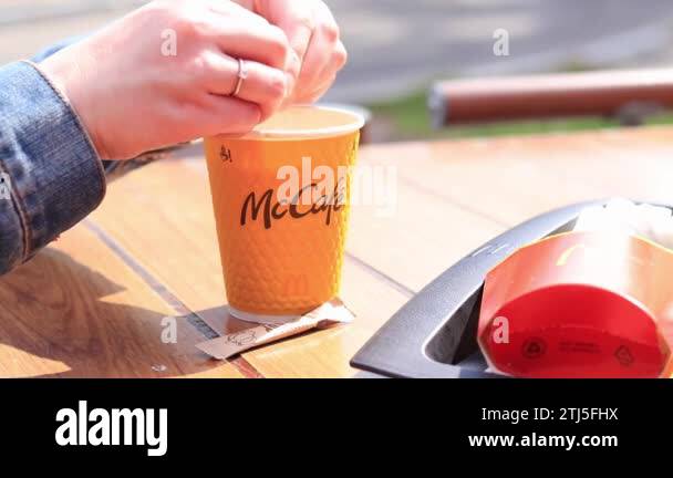 Kyiv, Ukraine - May 11, 2023: Woman pours sugar into a McDonald's latte ...