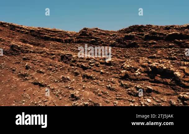 Woman hiker walking on cliff edge overlooking volcano with big barren ...