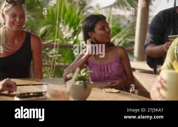 Woman waiter with a tray serves cocktails to multiracial women in ...