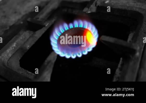 Bright saturated blue fire from an old dirty and rusty gas stove burner ...