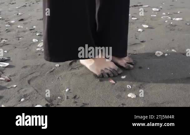 A tourist is playing with the sand using his feet on Tirang Beach ...