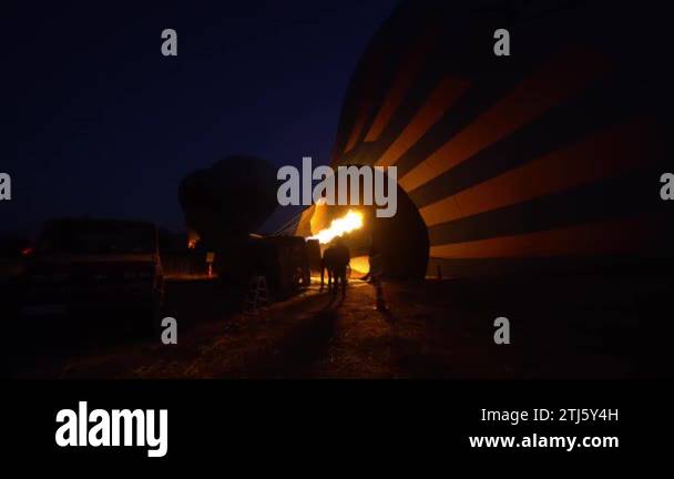 Close-up of balloon at night as it inflates for flight, burning burner ...