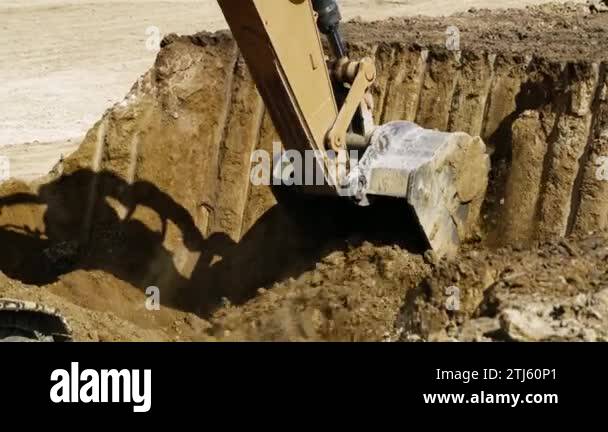 Close-up of an excavator bucket picking up soil in a quarry. The ...