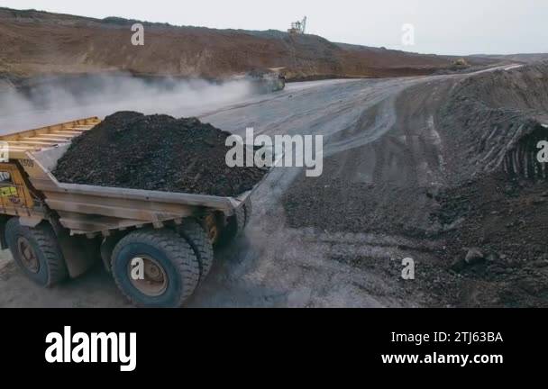 Haul truck loaded with soil drives away from the camera in the quarry ...