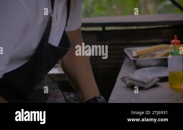 Pan up of a male chef preparing bread in an outdoor kitchen and ...