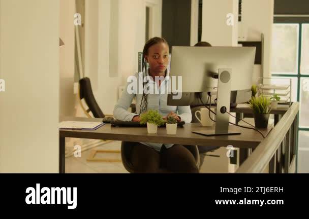 Startup employee working on computer in office with big windows, using data research to create ...
