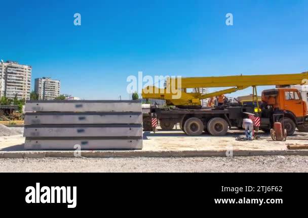 Unloading concrete plates by yellow crane at road construction site ...