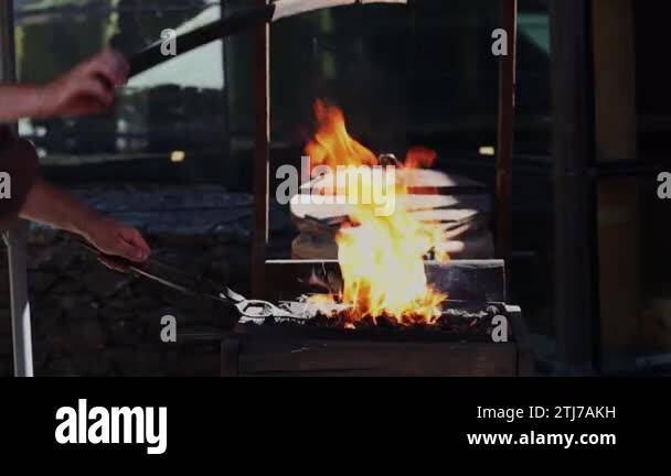 Middle aged caucasian male blacksmith of the medieval era forges iron ...