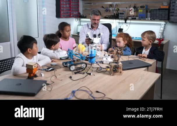 Zoom in enthusiastic male teacher showing a robot android for a group ...