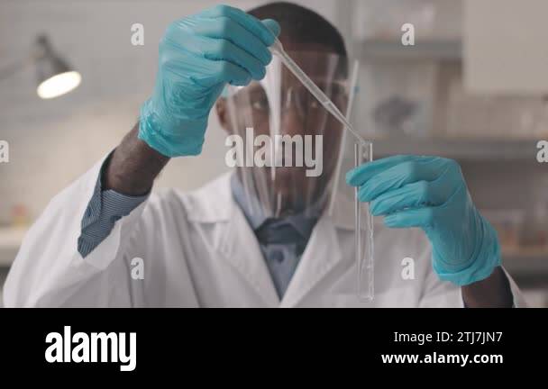 Chest up slowmo of young African American chemist in face shield and ...