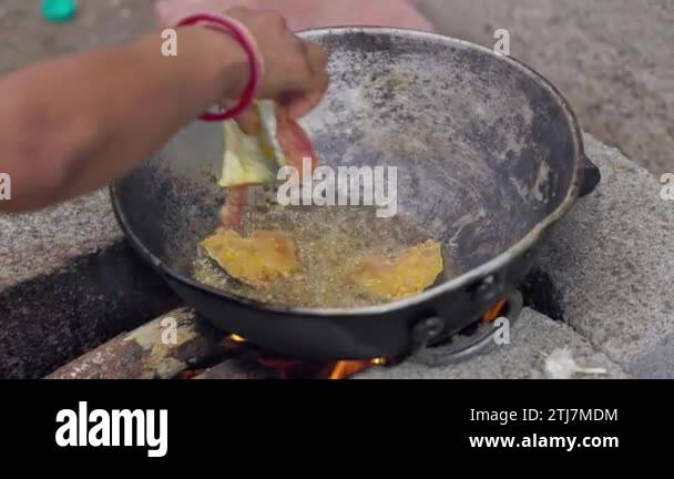 Indian woman frying the fish in the pan on the brick stove in ...