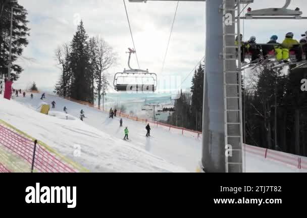 People go down the ski slope under the elevator in front of the ...