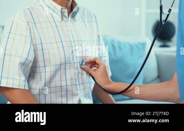 Caring young female doctor examining her contented senior patient with ...
