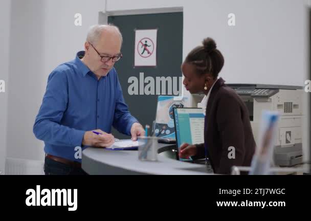 African american receptionist helping old man to fill in report papers ... African american receptionist helping old man to fill in report papers ...