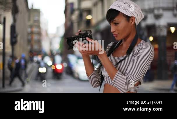 Modern black female takes photographs on her camera while out in the ...