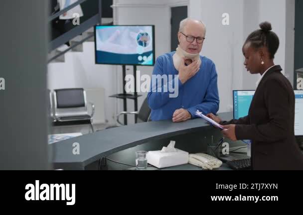 Female receptionist talking to man with medical neck collar, being in ...