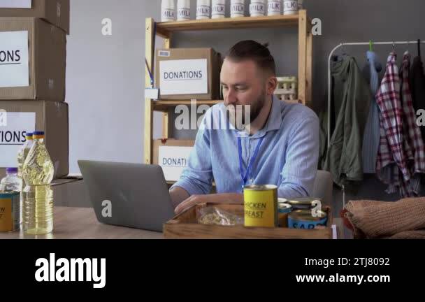 Man volunteer using laptop computer while preparing food for donation ...