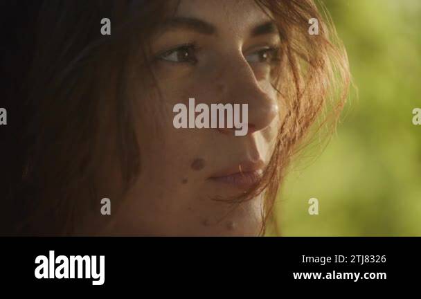 Handheld close up catching sunbeam on curly caucasian woman face with ...