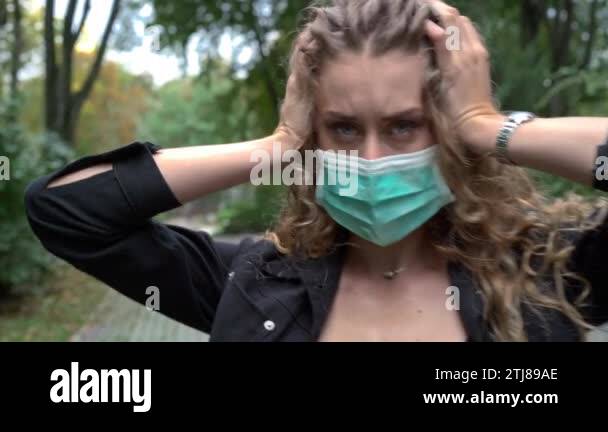 Close-up woman in coronavirus face mask holding head in hands having ...