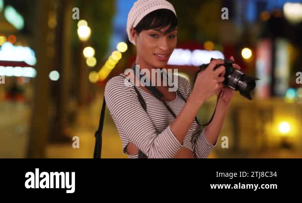 Hip African millennial girl out taking photos at night turns to the ...