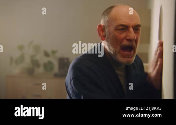 Irritated, angry elderly and adult man hit the wall with hands, yell at ...