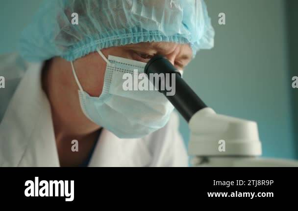 Close up of middle-aged doctor in medical mask, hat and lab coat ...
