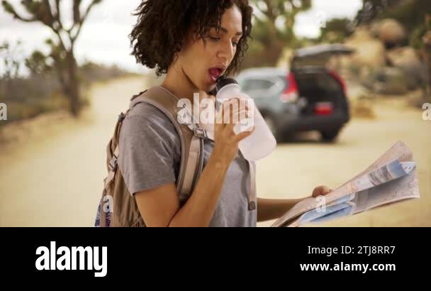 Lost female hiker looking at map of Mojave Desert. Young black woman ...