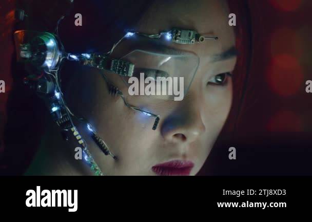 Focused asian girl in cyberpunk attire works on the computer. Wearing ...