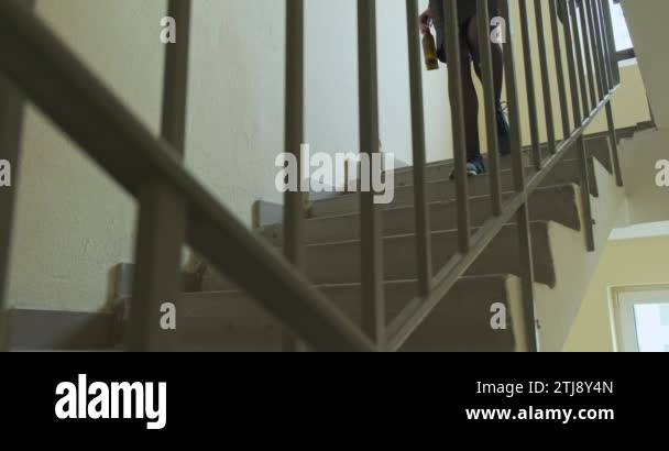 Drunk unrecognizable woman in a dress descends the stairs with a bottle ...