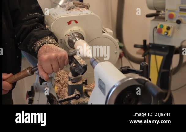 Man carpenter using chisel for shaping piece of wood on turning lathe ...