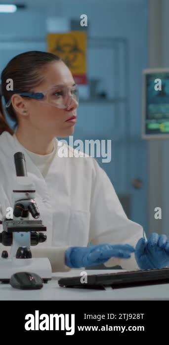 Vertical video: Lab worker using magnifying glass on microscope to work ...